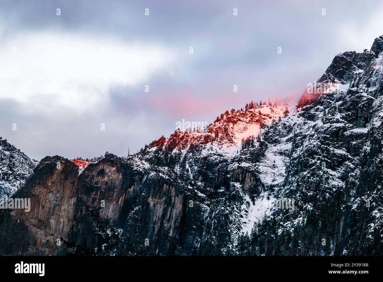 Snow-capped peaks in Yosemite with fiery sunset light on the ridge ...