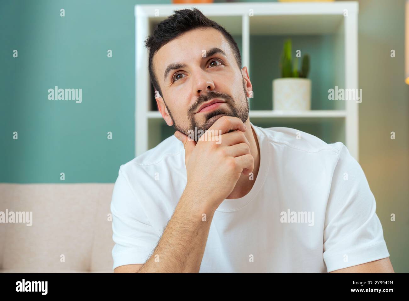 Thoughtful young man facing the camera while leaning forward on the ...