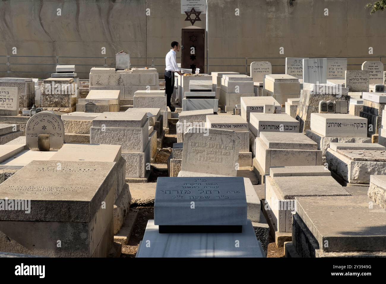 A Haredi Jewish man prays over a tomb in Sanhedria Cemetery Jewish ...