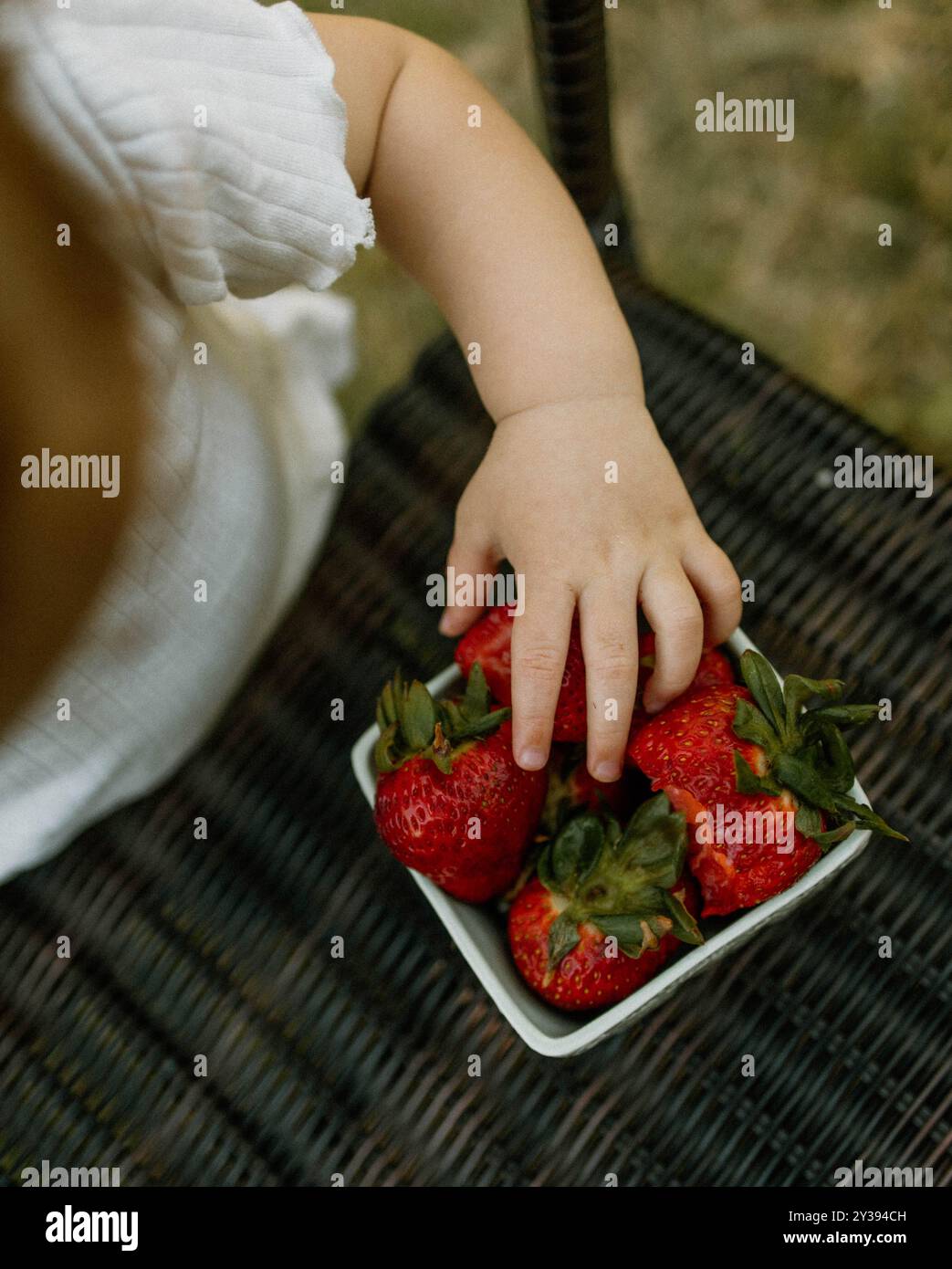Toddler hand grabbing a strawberry from a bowl outside Stock Photo - Alamy
