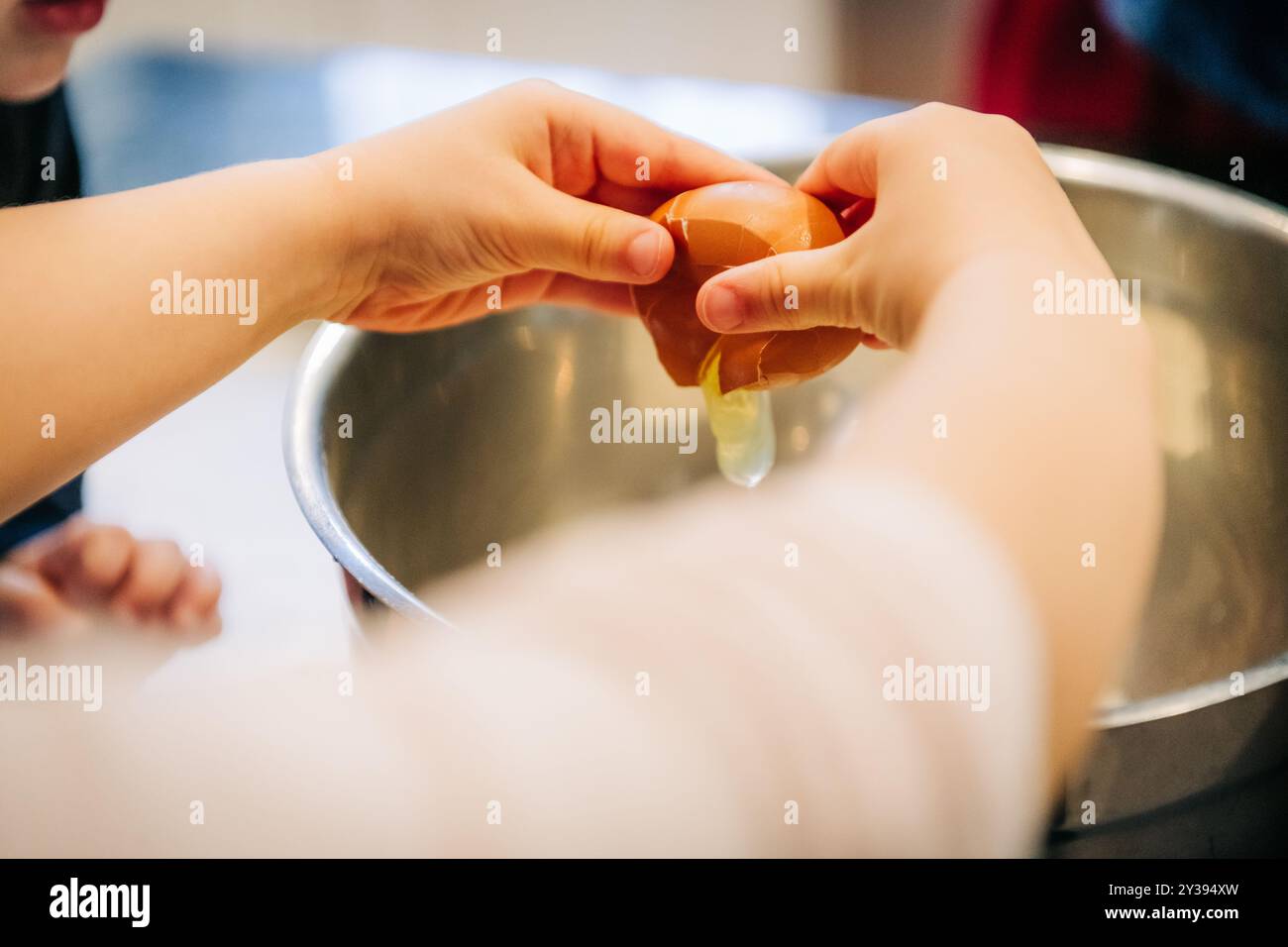 Close-up of hands cracking an egg over a mixing bowl while baking Stock ...