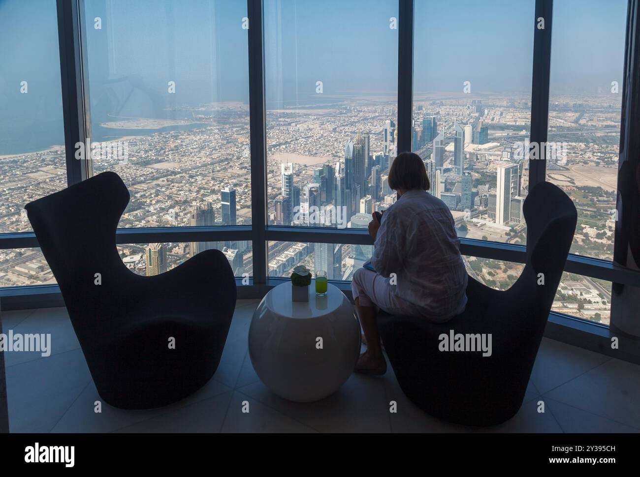 Tourist sitting on a chair with the view from the top of the Burj ...