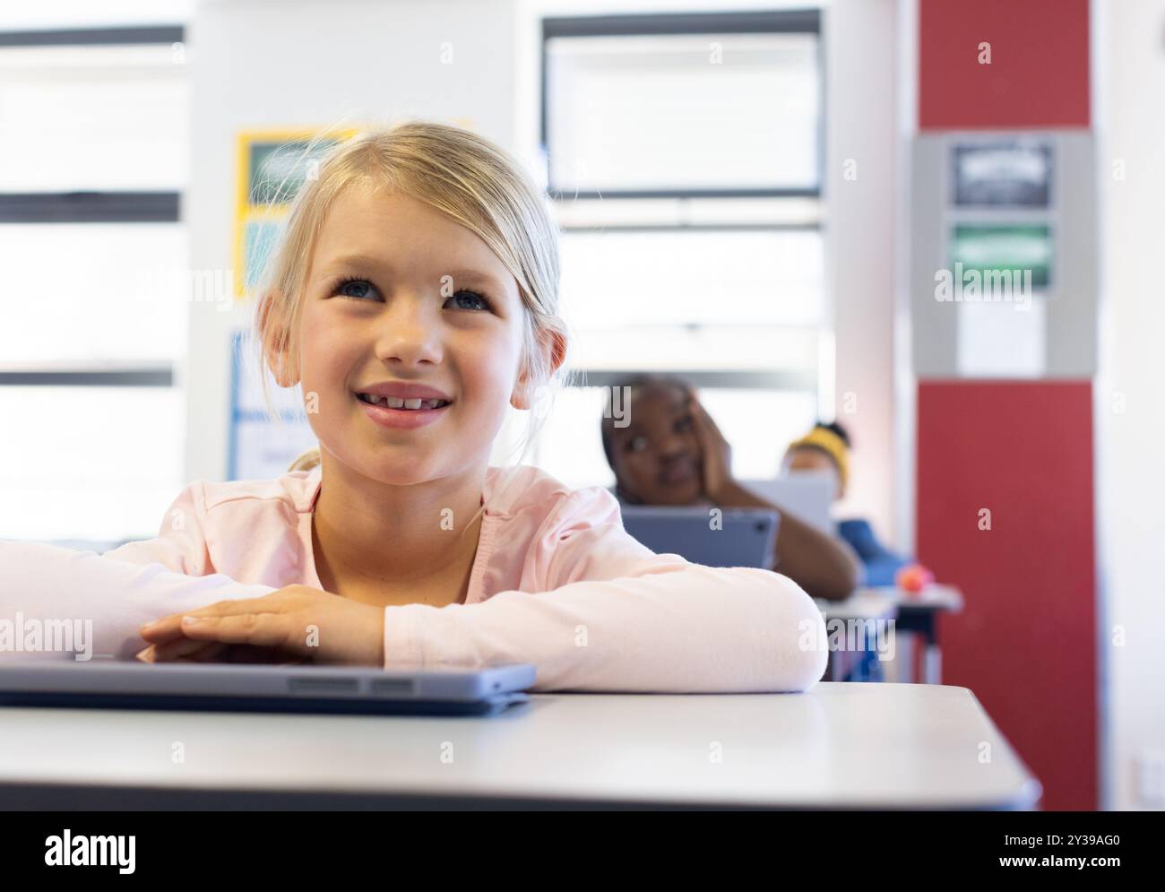 In school, girl smiling and using laptop in classroom, focusing on ...