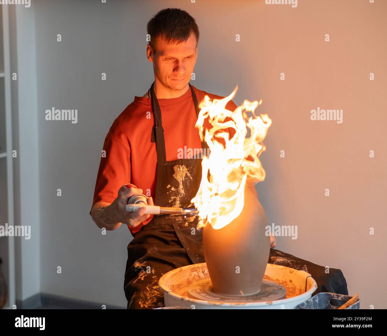 A potter burns a jug with a gas burner on a potter's wheel Stock Photo ...