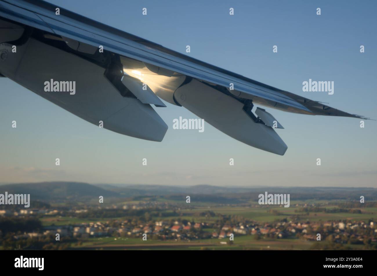 Setting sun glints on the mechanisms underneath an airliner wing as it ...