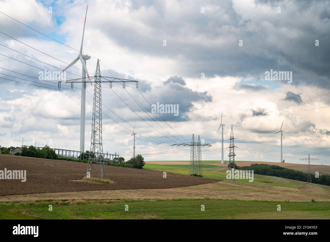 Electric power pole and windmills in a field, transformation to ...