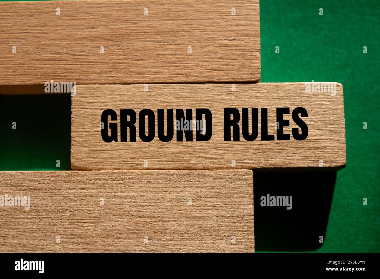 Ground rules message written on wooden block with green background ...