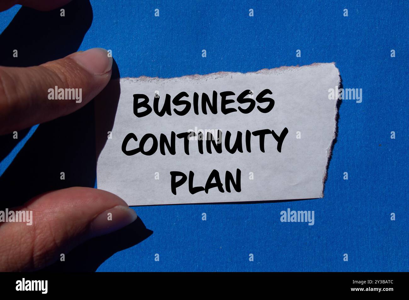 Business continuity plan message written on ripped torn paper with blue ...
