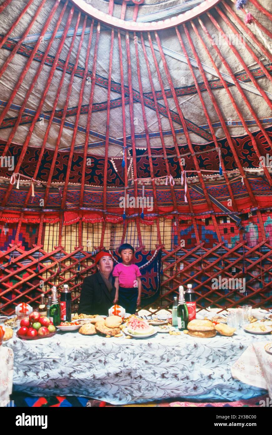 An elderly woman and a child inside a traditional yurt, showcasing ...