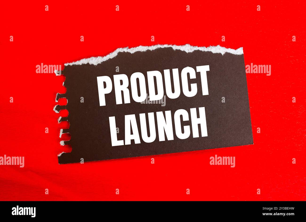 Product launch message written on ripped torn black paper piece with ...