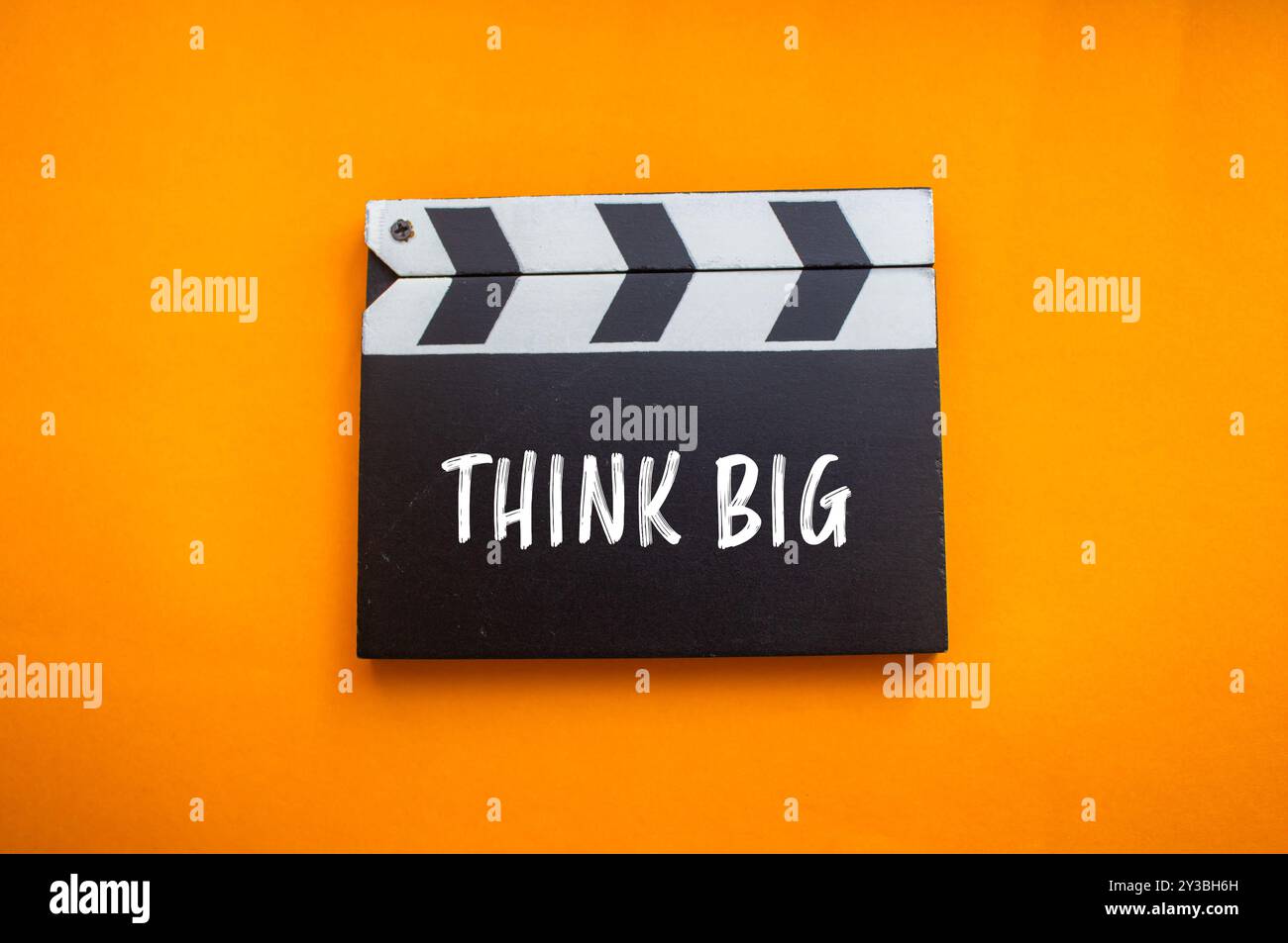 Think big message written on movie clapper board with orange background ...