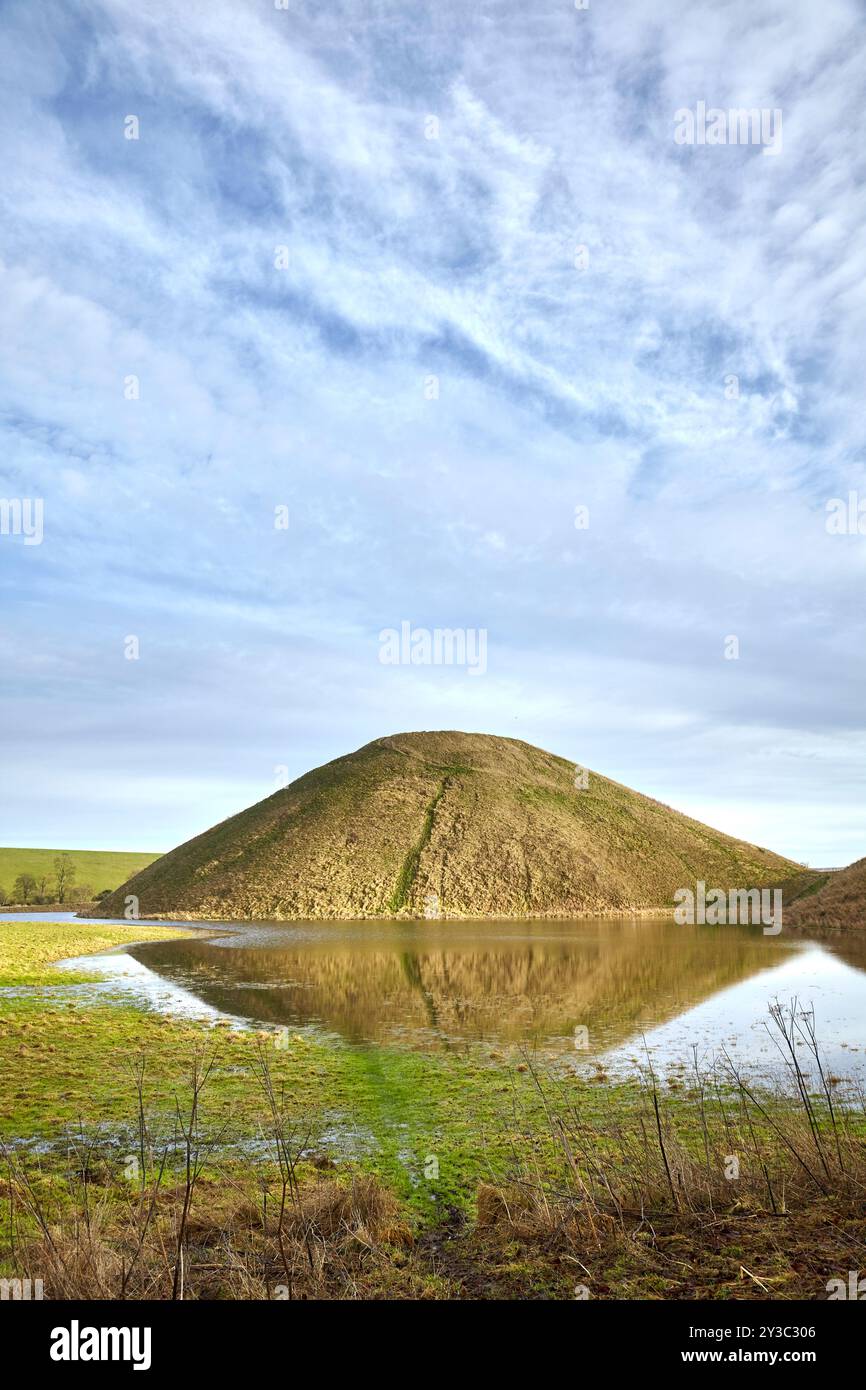 A peaceful hill reflecting in a still body of water with a bright blue ...