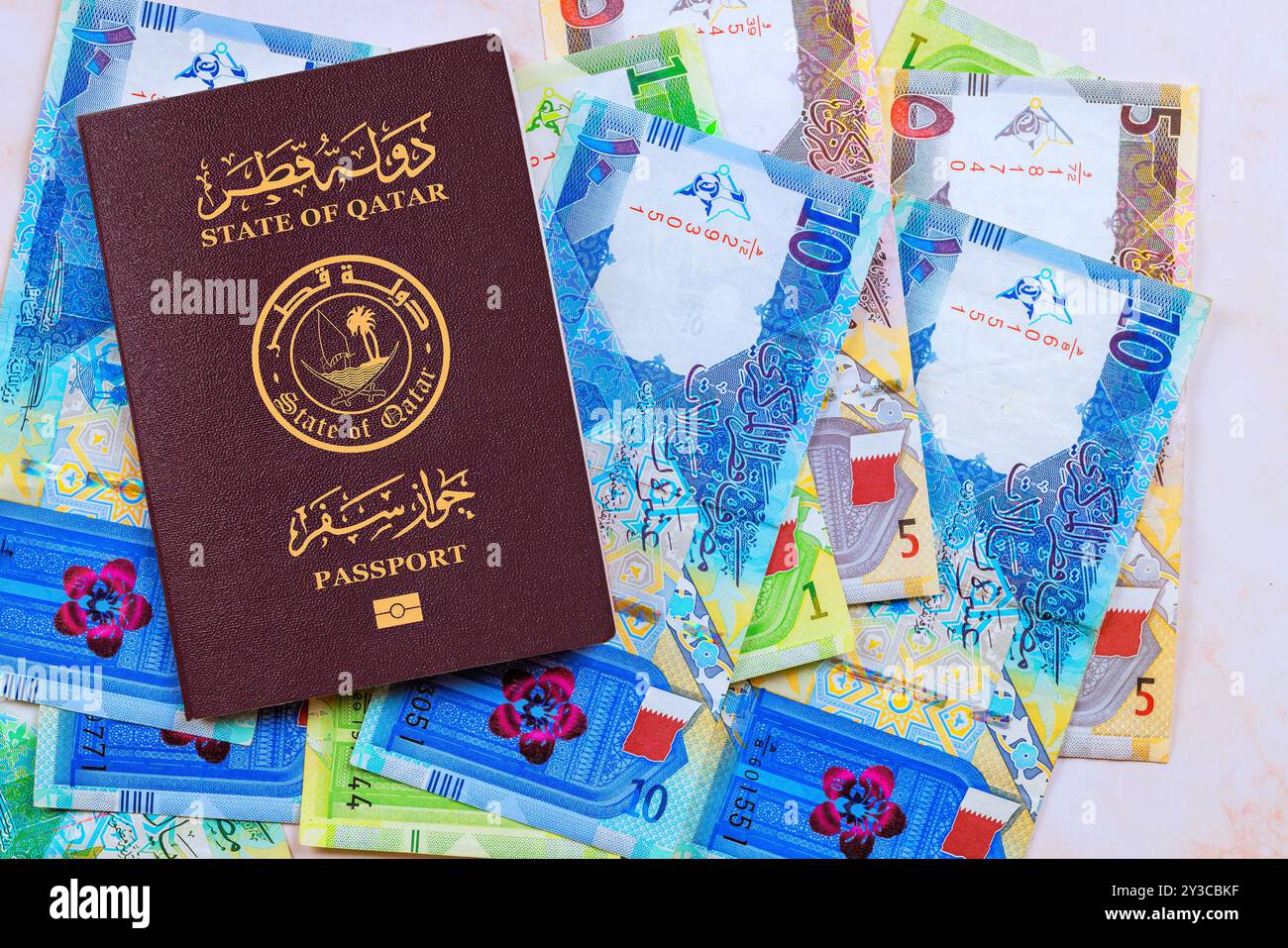 Passport issued by State of Qatar with Qatari banknotes in currency ...