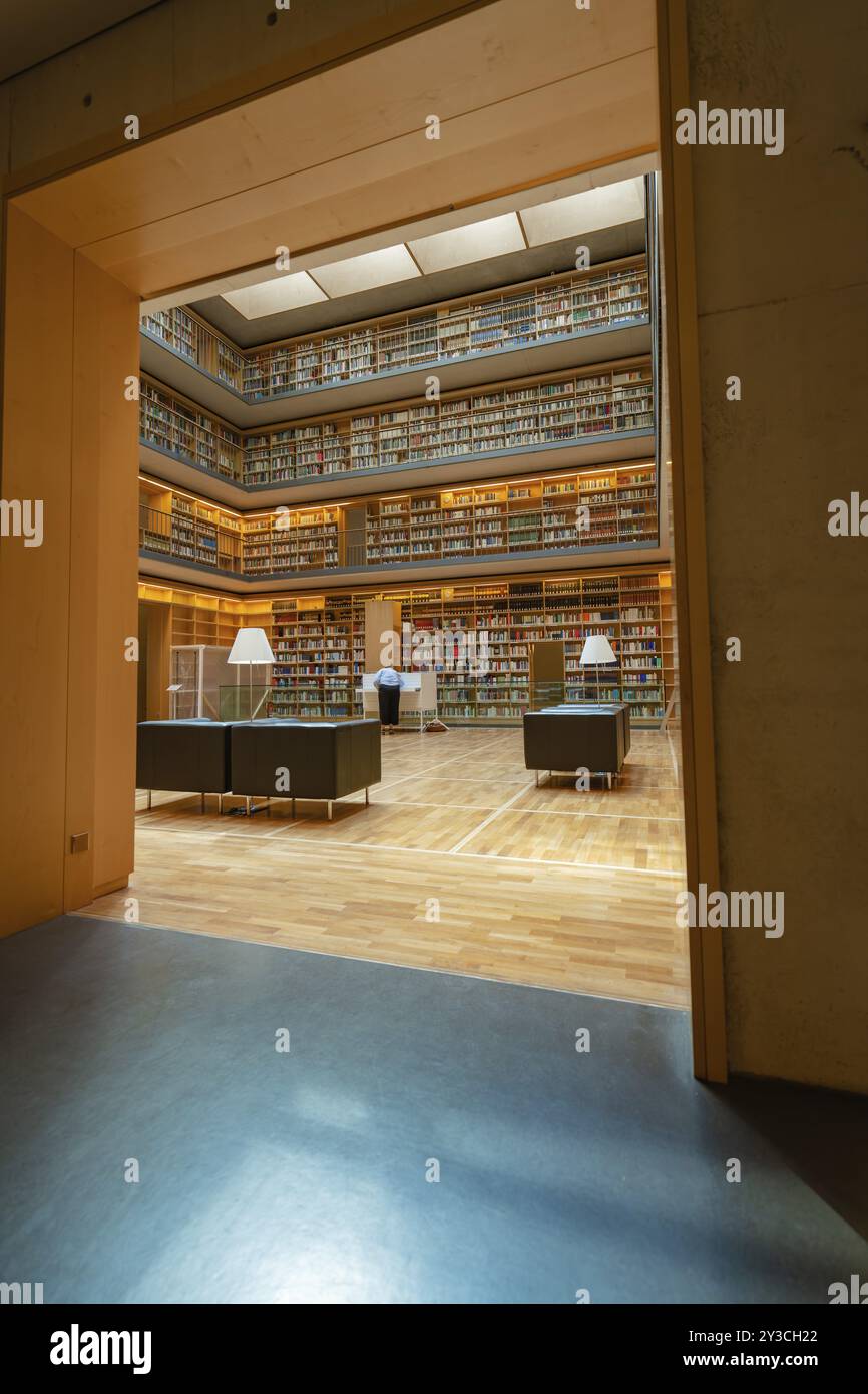 Interior of a modern library, open and bright with numerous bookshelves and reading areas ...