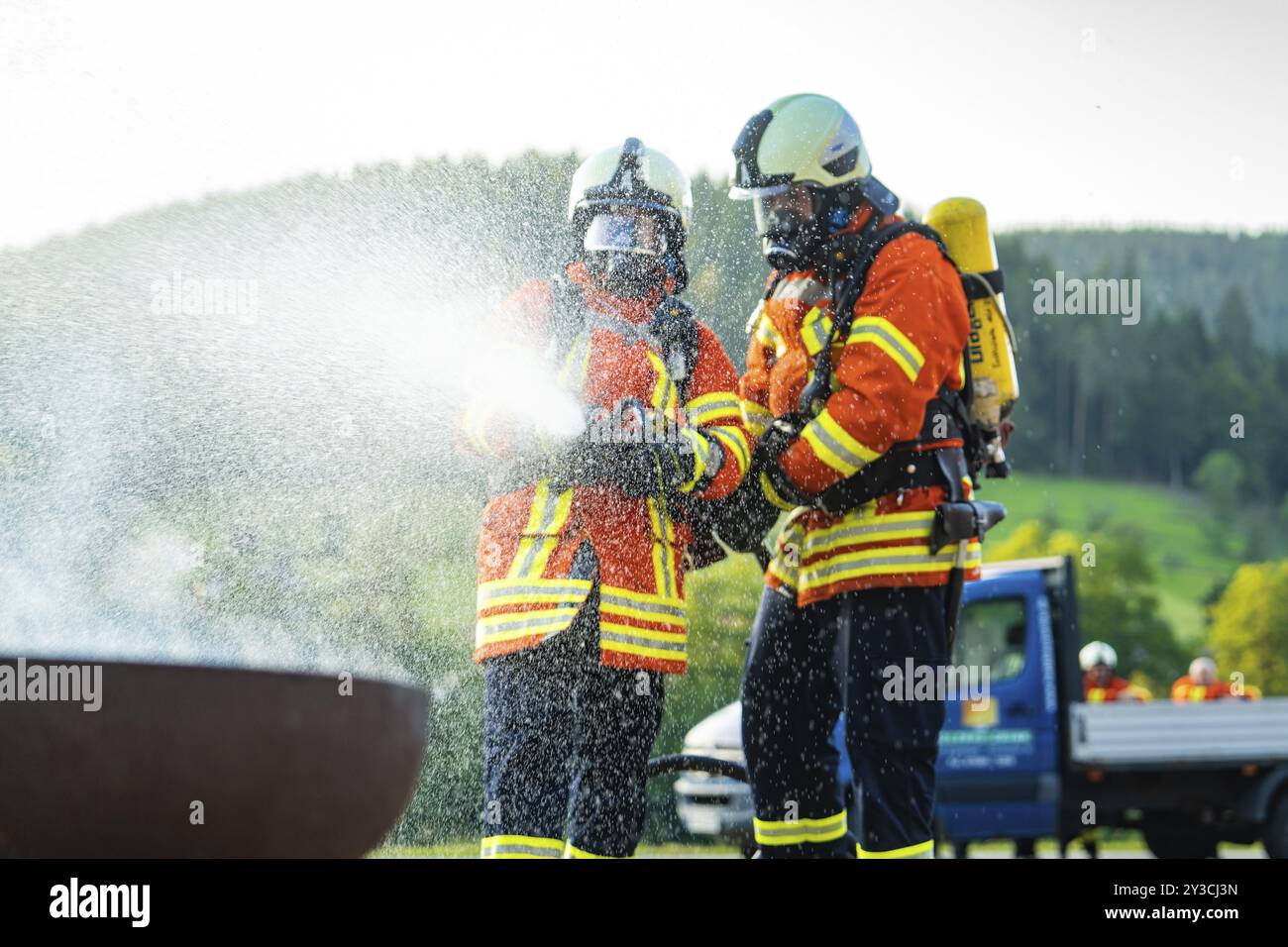 Two firefighters fighting a fire with a fire hose and wearing striking ...