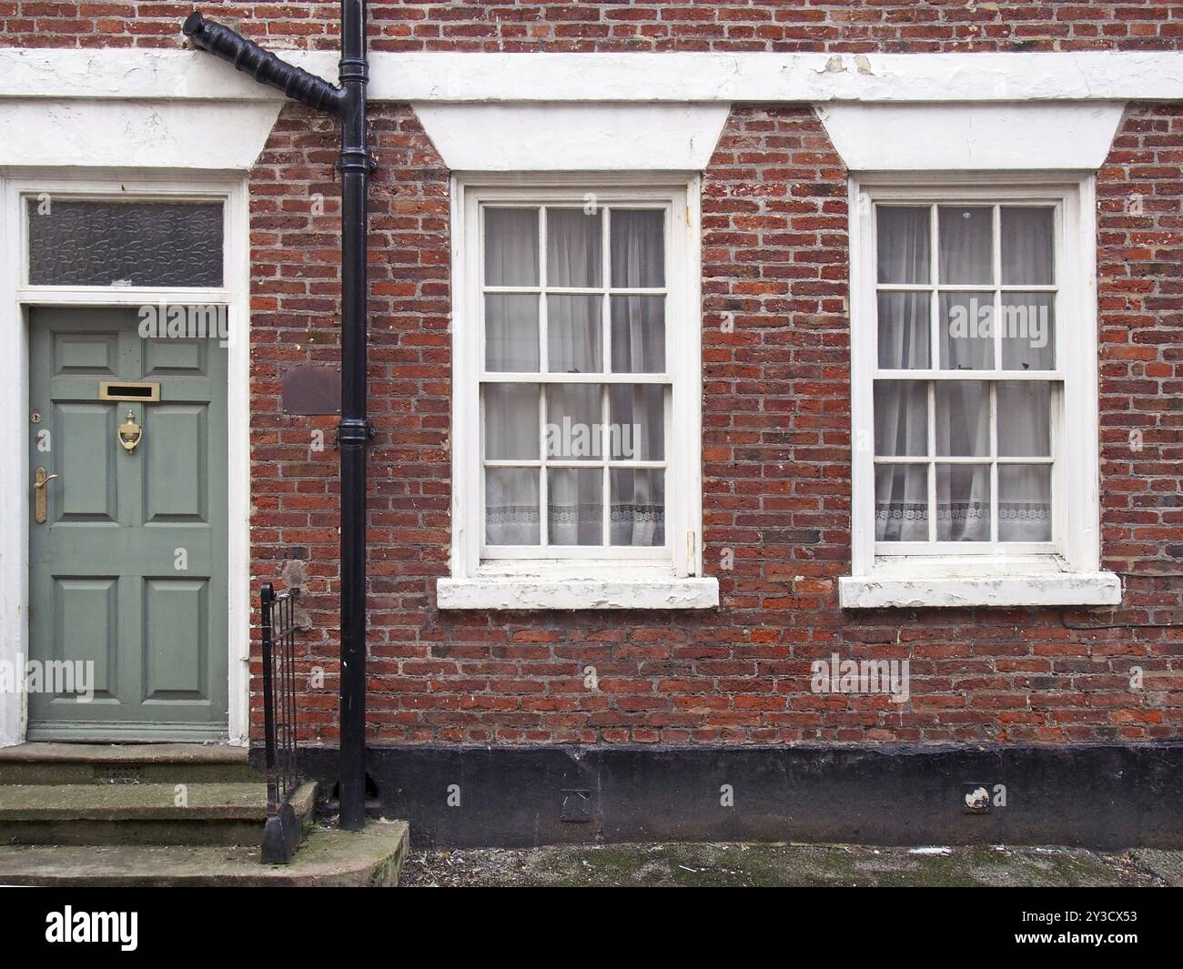 Front view of a typical old english terraced brick house with yellow ...