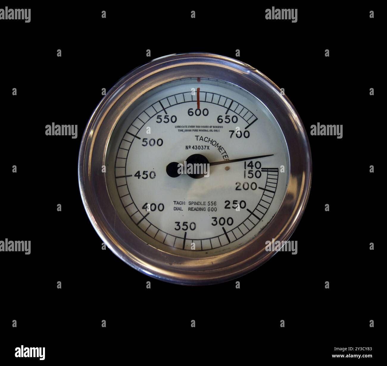 An old round metal industrial tachometer on a black background with ...