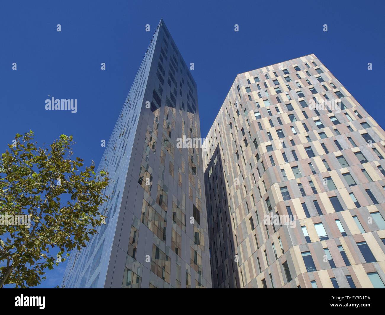 Two modern skyscrapers with glass facades rise into the blue sky ...
