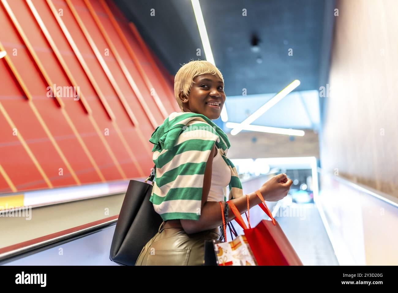 African woman using mechanical escalator in a shopping mall and turning ...