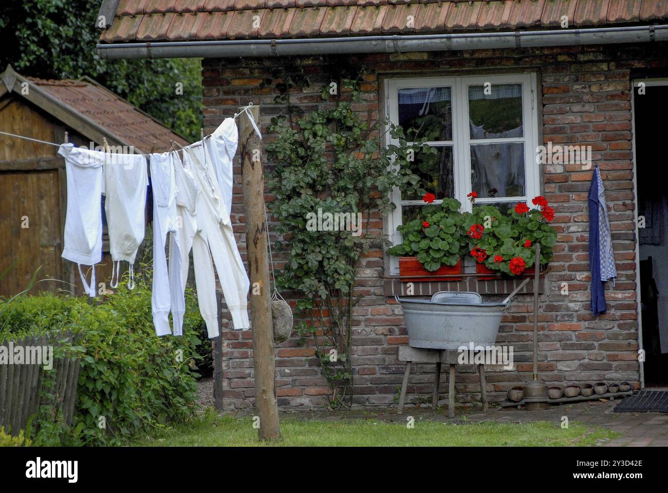 White washing hanging on a washing line in front of a brick house with ...