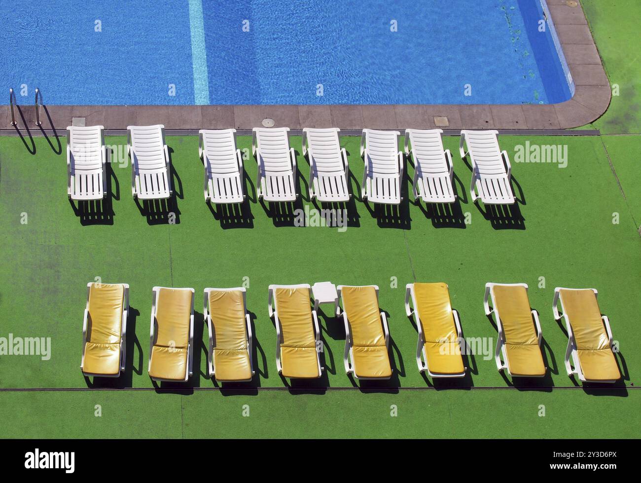 View of an outdoor swimming pool from above with sun loungers an sunlit ...