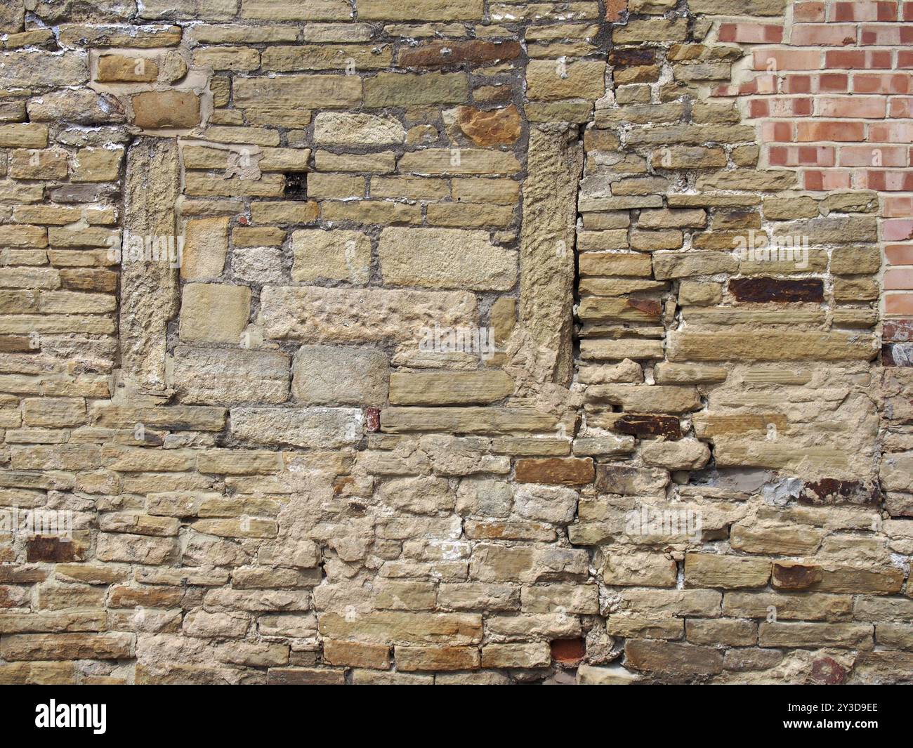 An old much repaired and patched wall mad of mixed types of bricks and ...