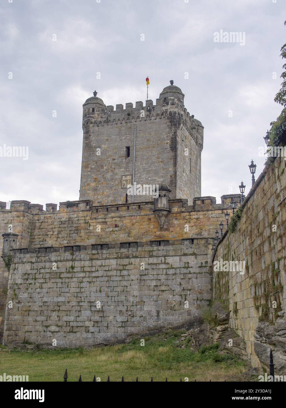 Large castle complex with high stone wall and tower on which a flag ...