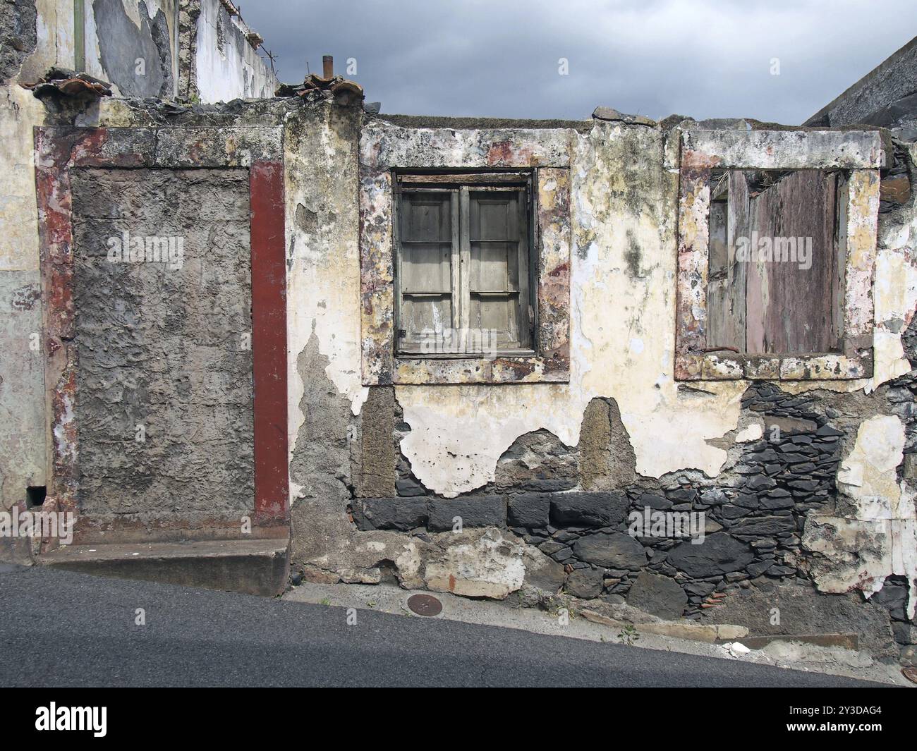 An old ruined house partly collapsed on a sloping street with a blocked ...
