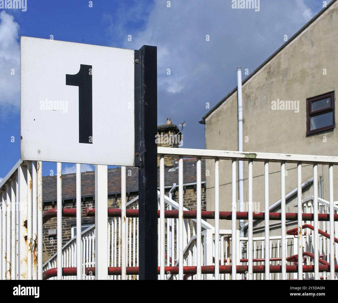 A railway station platform sign with the number 1 next to shabby ...