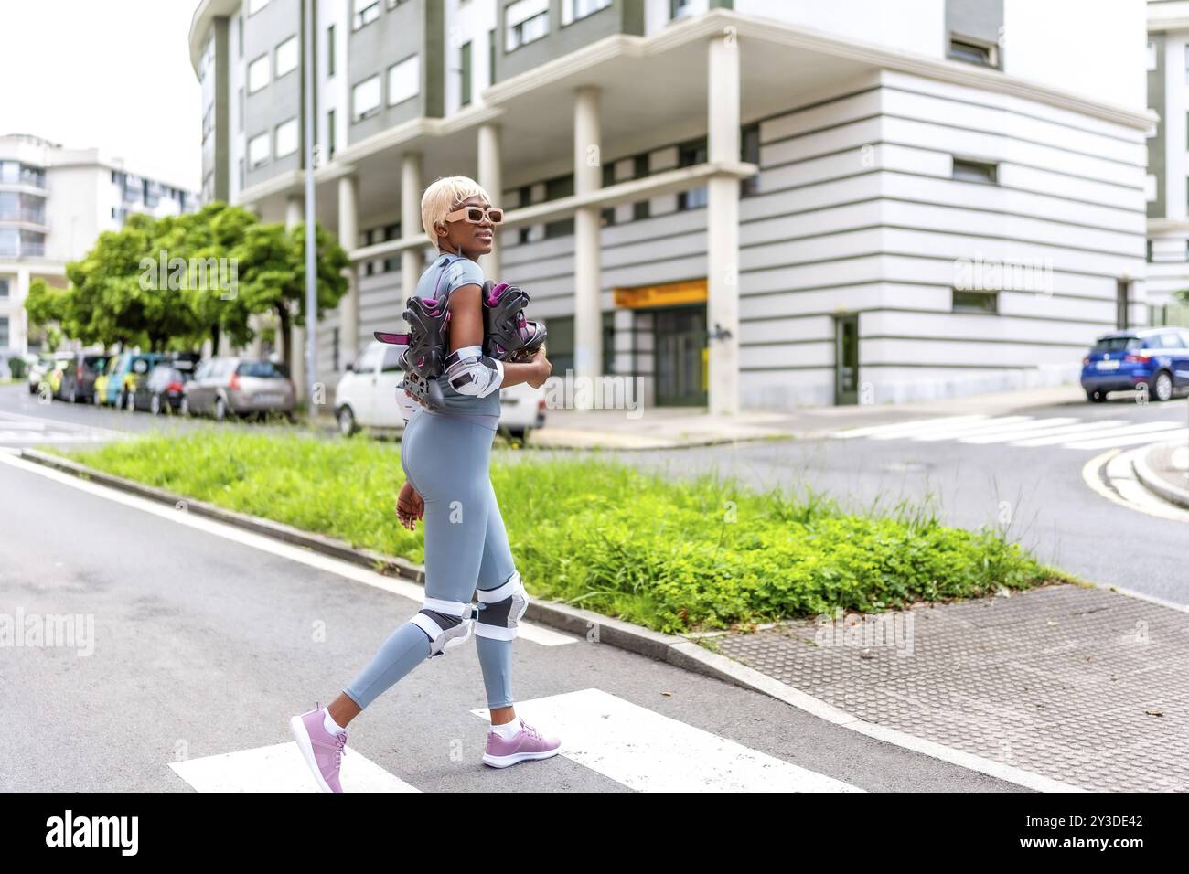 Full length side view of an african woman skater walking across the ...