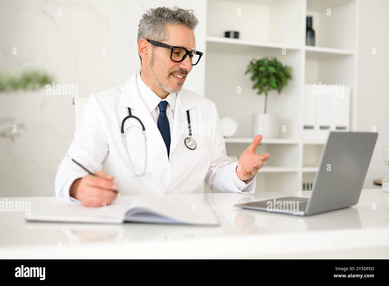 A mature doctor with grey hair is discussing a topic with a patient ...