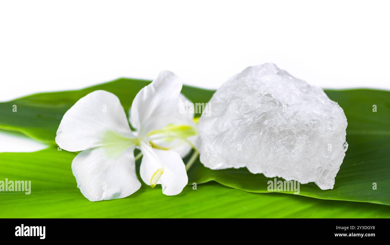 White crystal clear alum cube on green leaf isolated on white ...