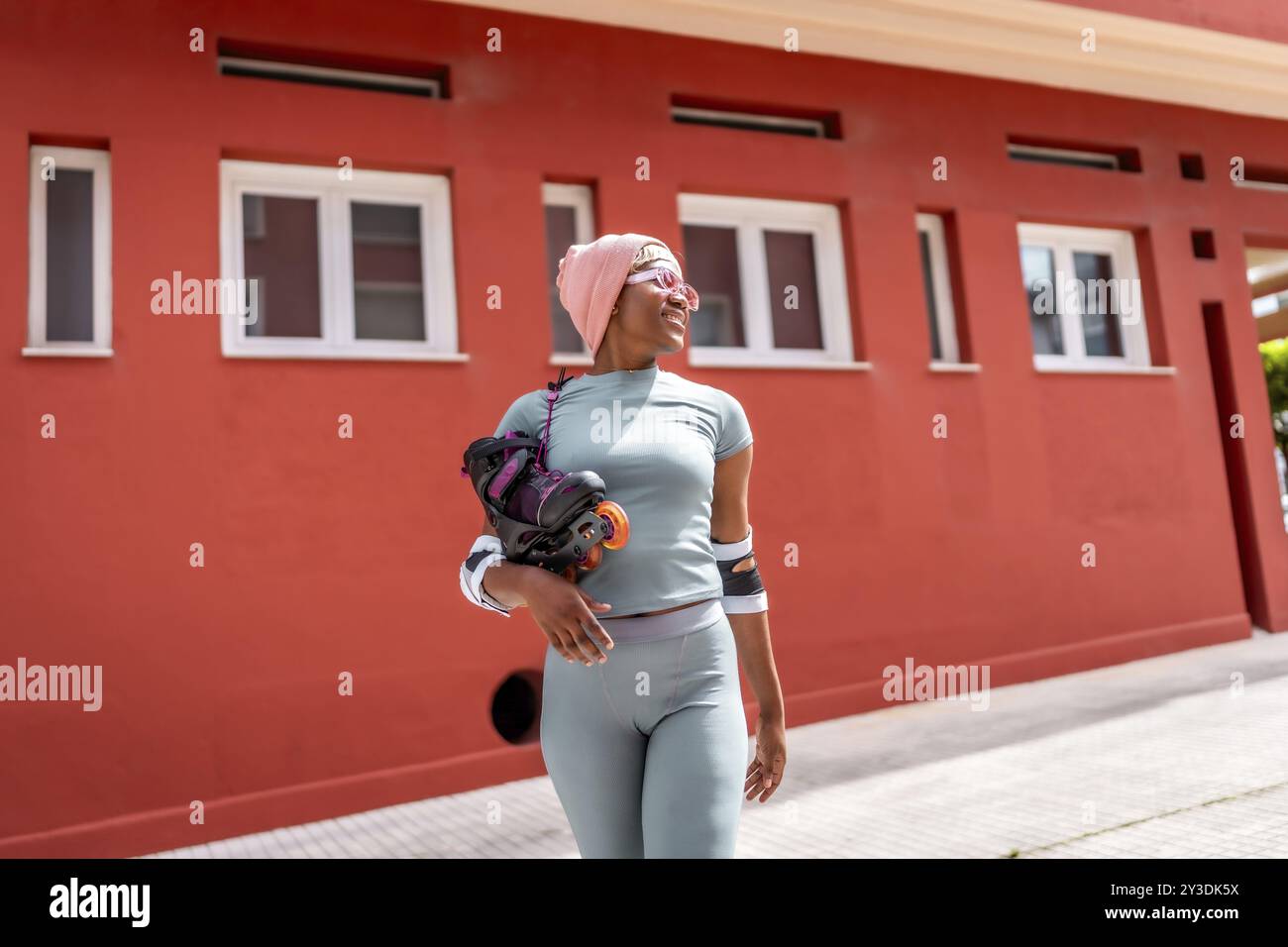 Urban african woman with hat and sunglasses walking carrying inline ...