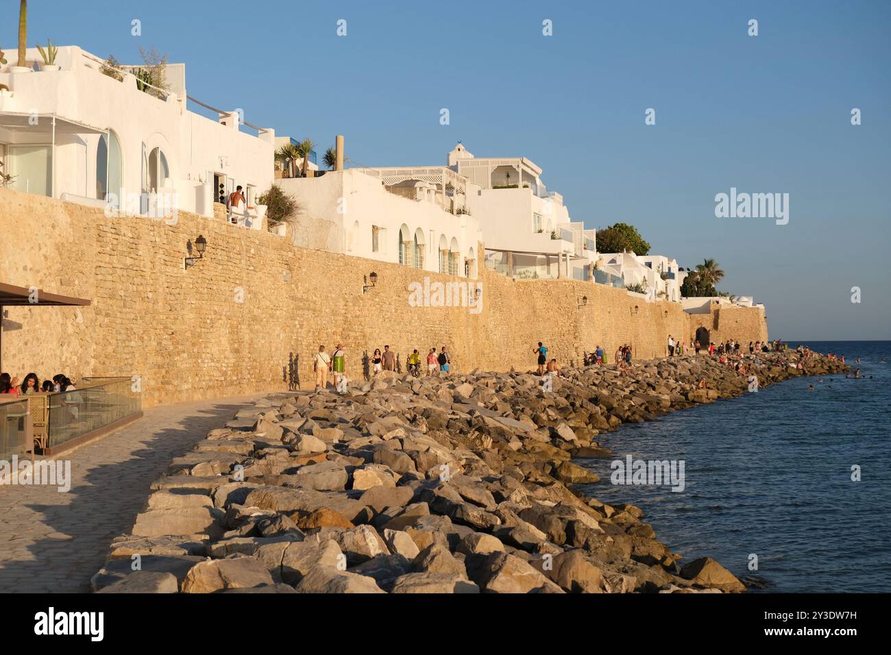 People walk between the sea and the old medina of Hammamet, a popular ...