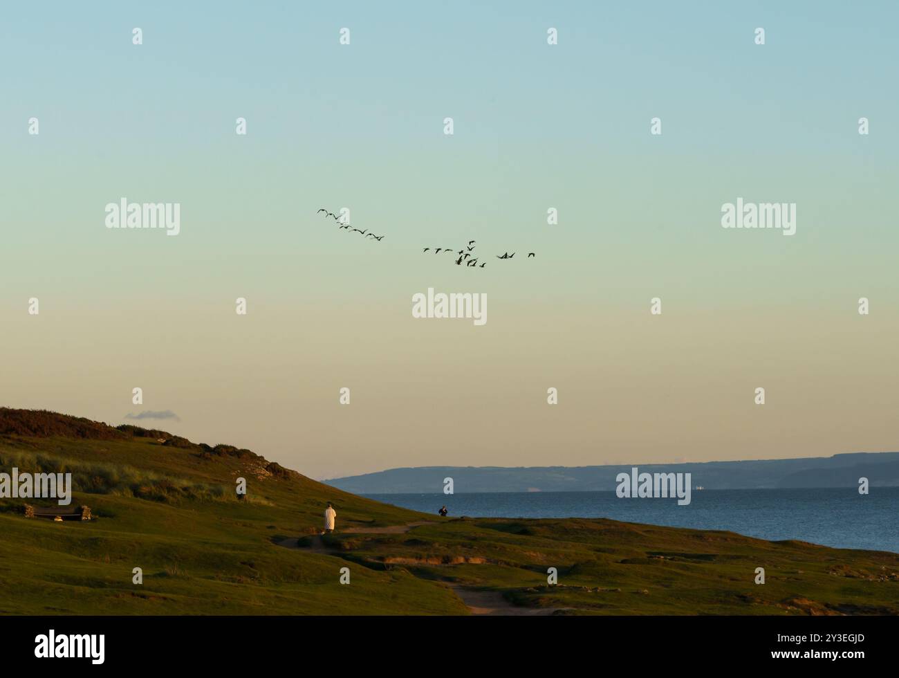 A woman and a lone man walk in opposite directions along the dunes at ...