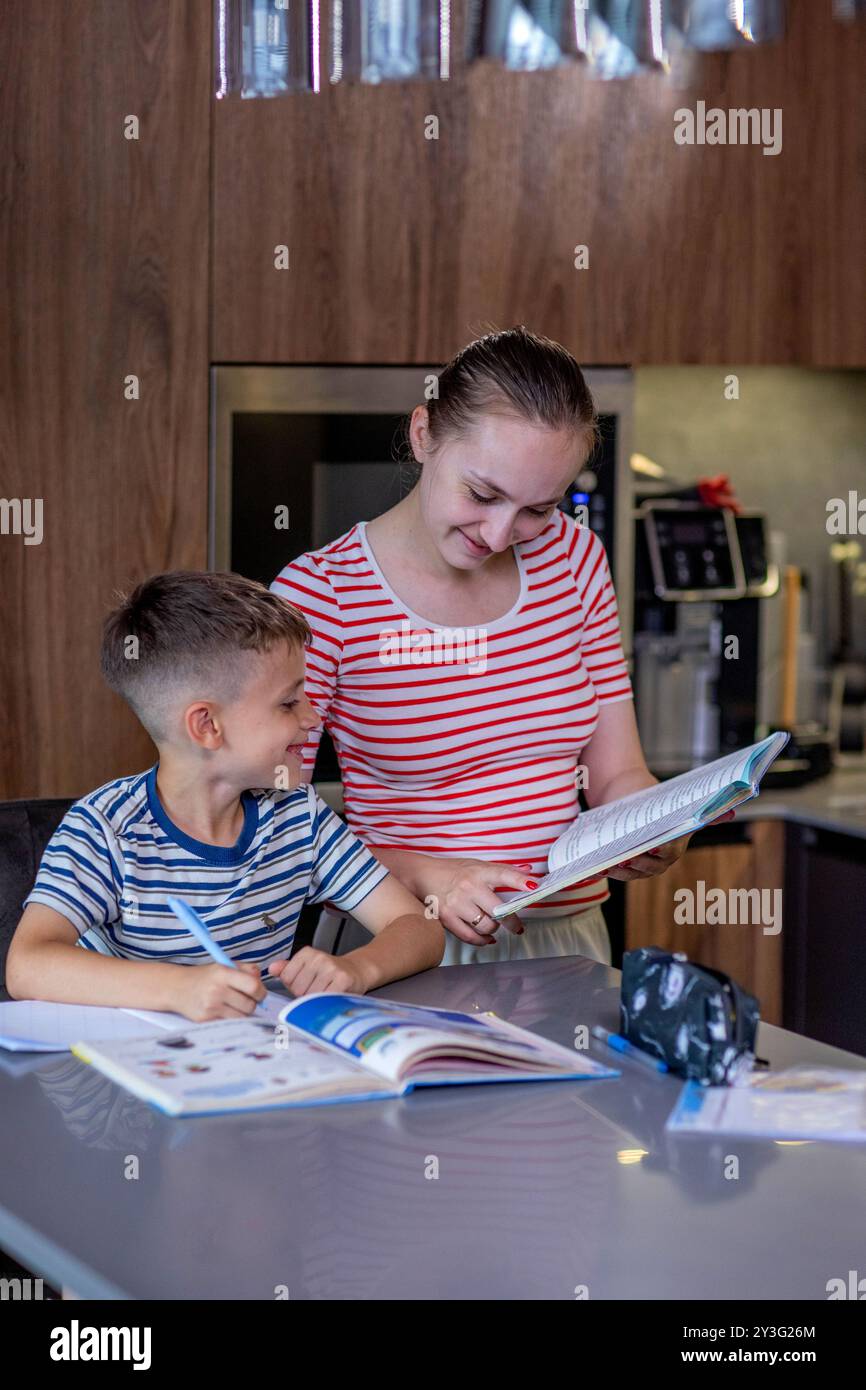 Mother helping son with homework in kitchen at home Stock Photo - Alamy