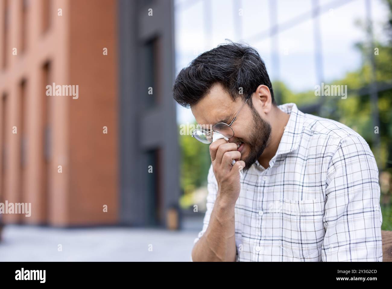 Close-up photo of a young sick Indian man sitting outside on the street ...