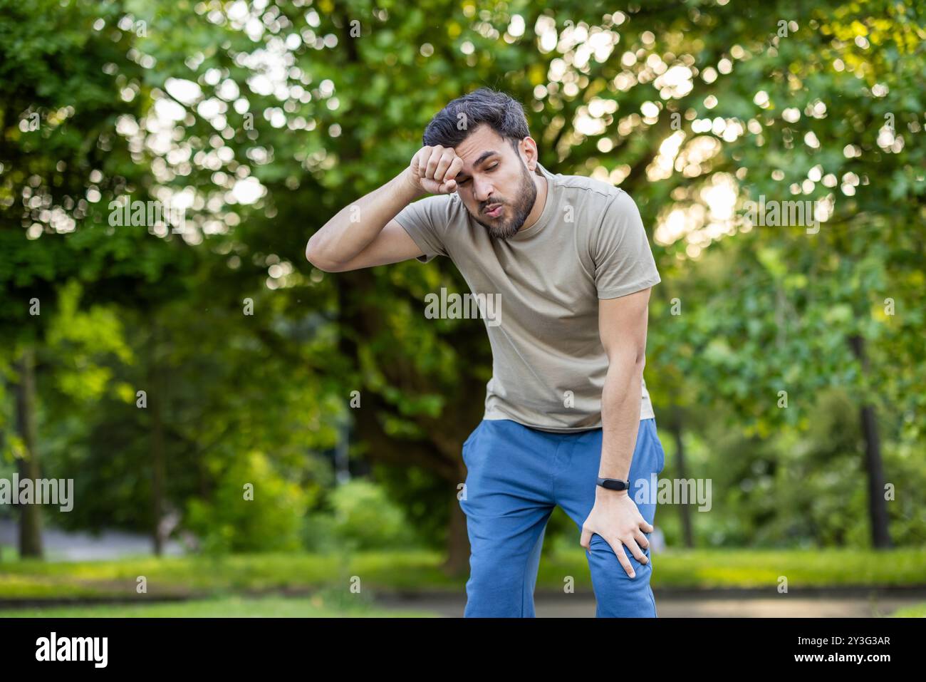 Exhausted athlete resting outdoors after intensive workout, surrounded ...