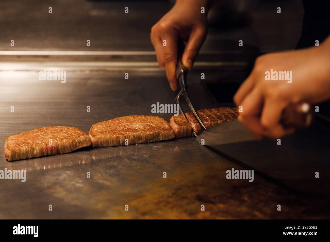 Cooked and sliced A5 Japanese wagyu steak being prepared on grill in an ...