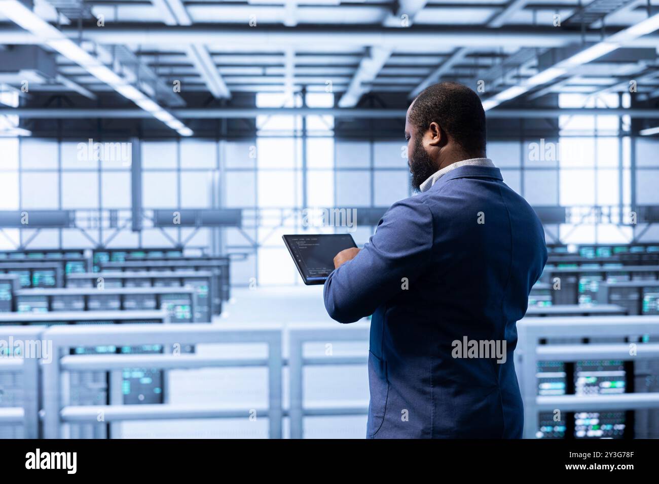 Employee in server hub using tablet to monitor energy consumption across supercomputer rigs ...