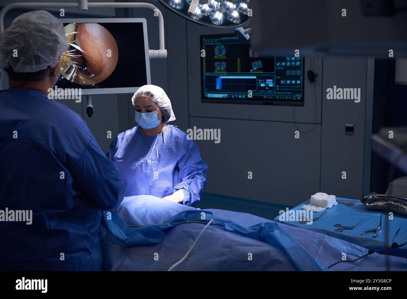 Surgeons performing surgery under bright operating lights Stock Photo ...