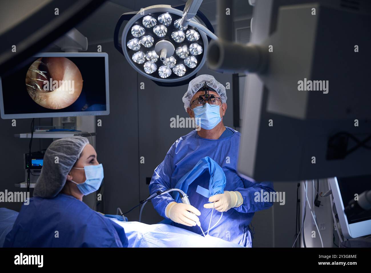 Surgeon wearing mask, focused on surgery Stock Photo - Alamy
