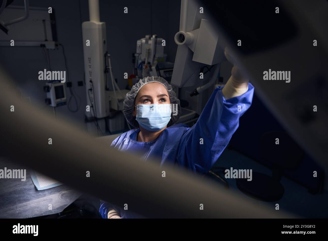 Female assistant reaches to adjust an overhead surgical light Stock ...