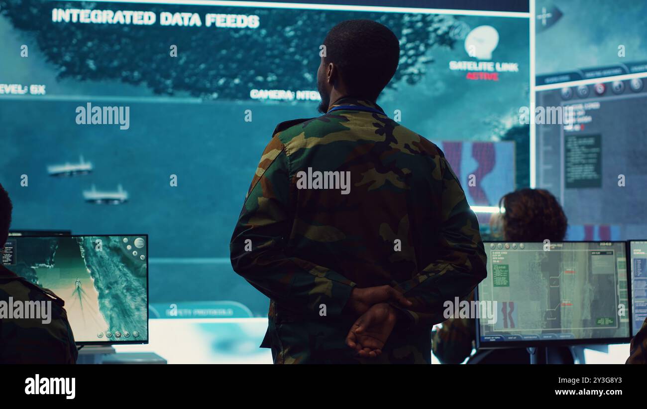 Army officer examining satellite surveillance footage on a big screen ...