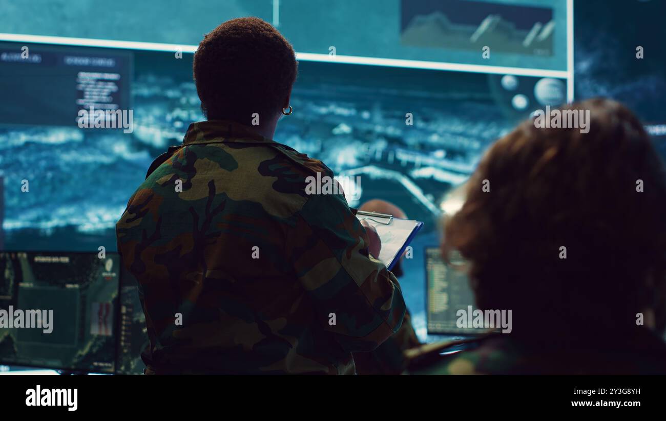 Female brigadier general gather intelligence reports on a big screen ...