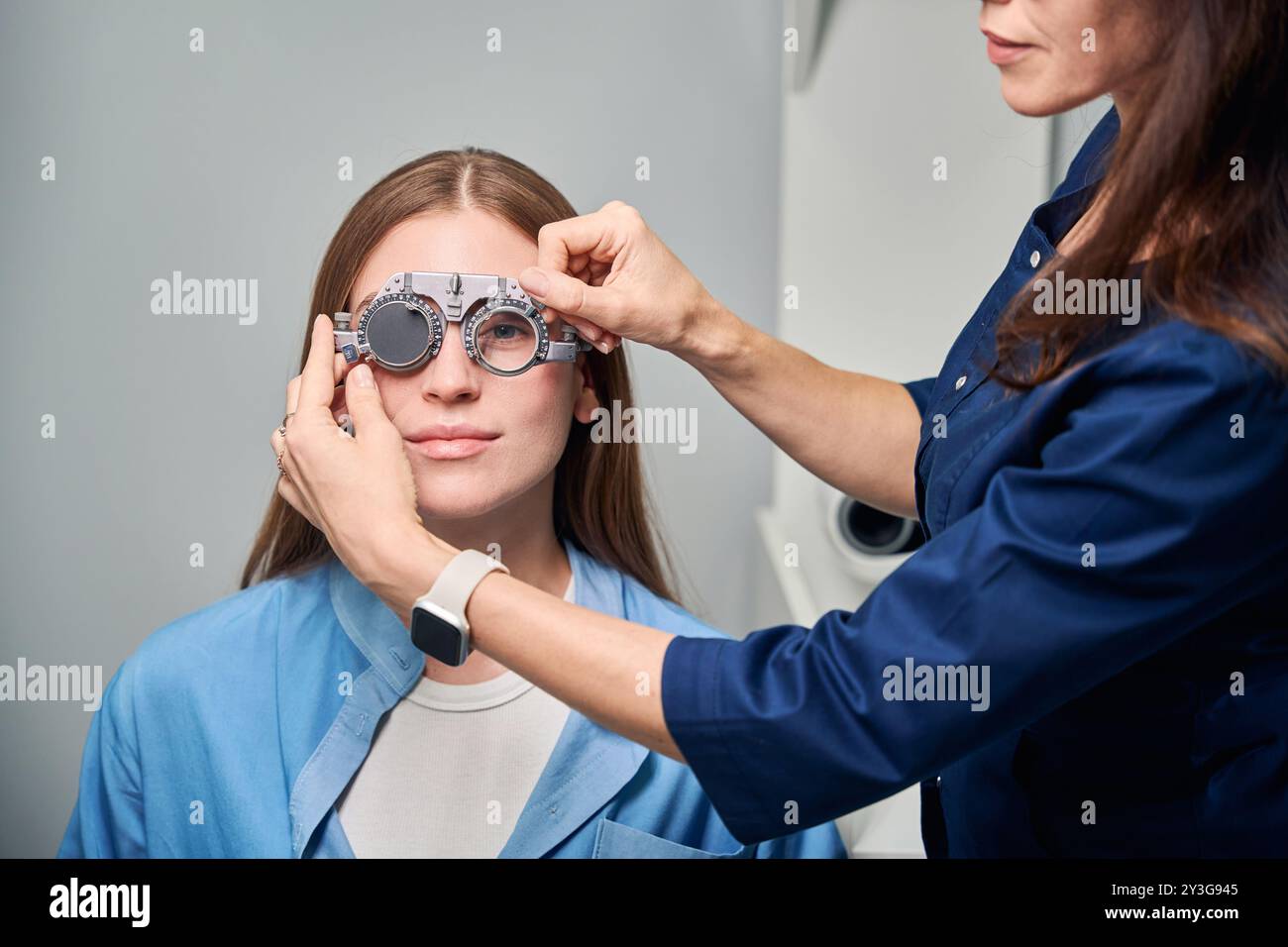 Female doctor optometrist adjusting trial frame on patients face Stock ...