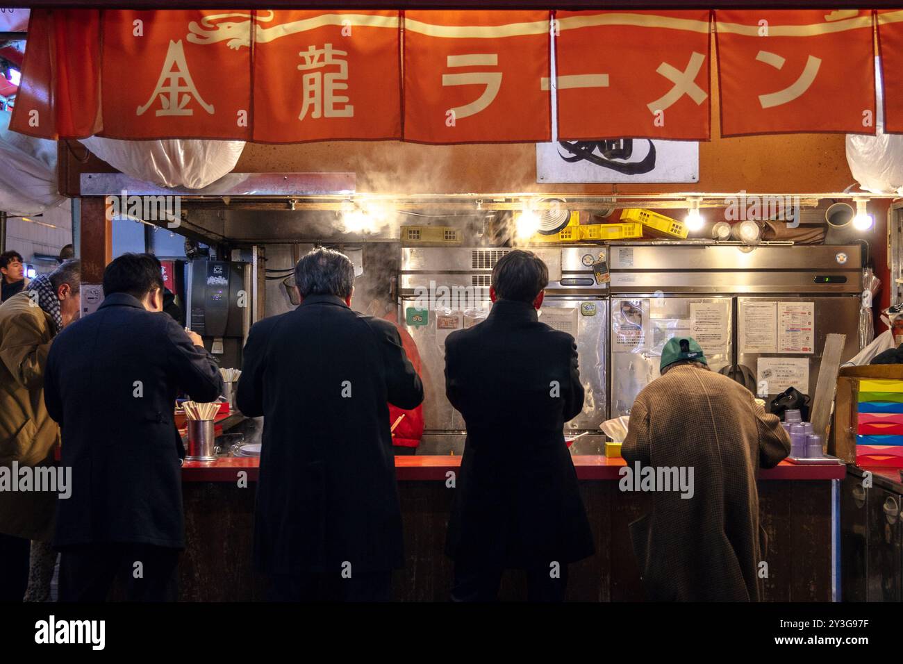 Group standing and eating at street food stall at night | Osaka, Japan ...
