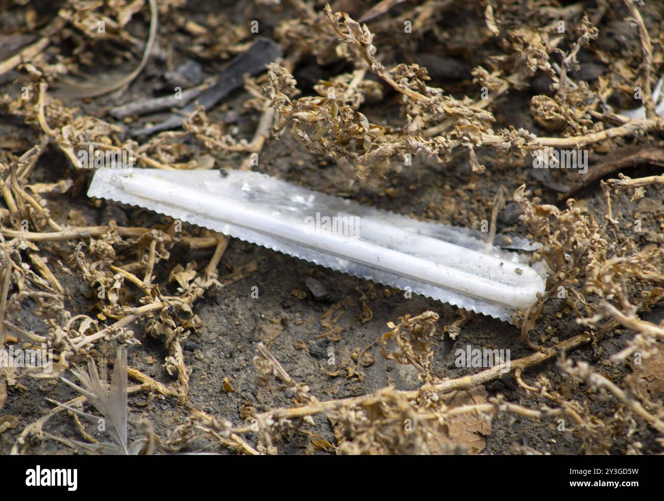 white straw in plastic packaging for juice box left on ground Stock ...