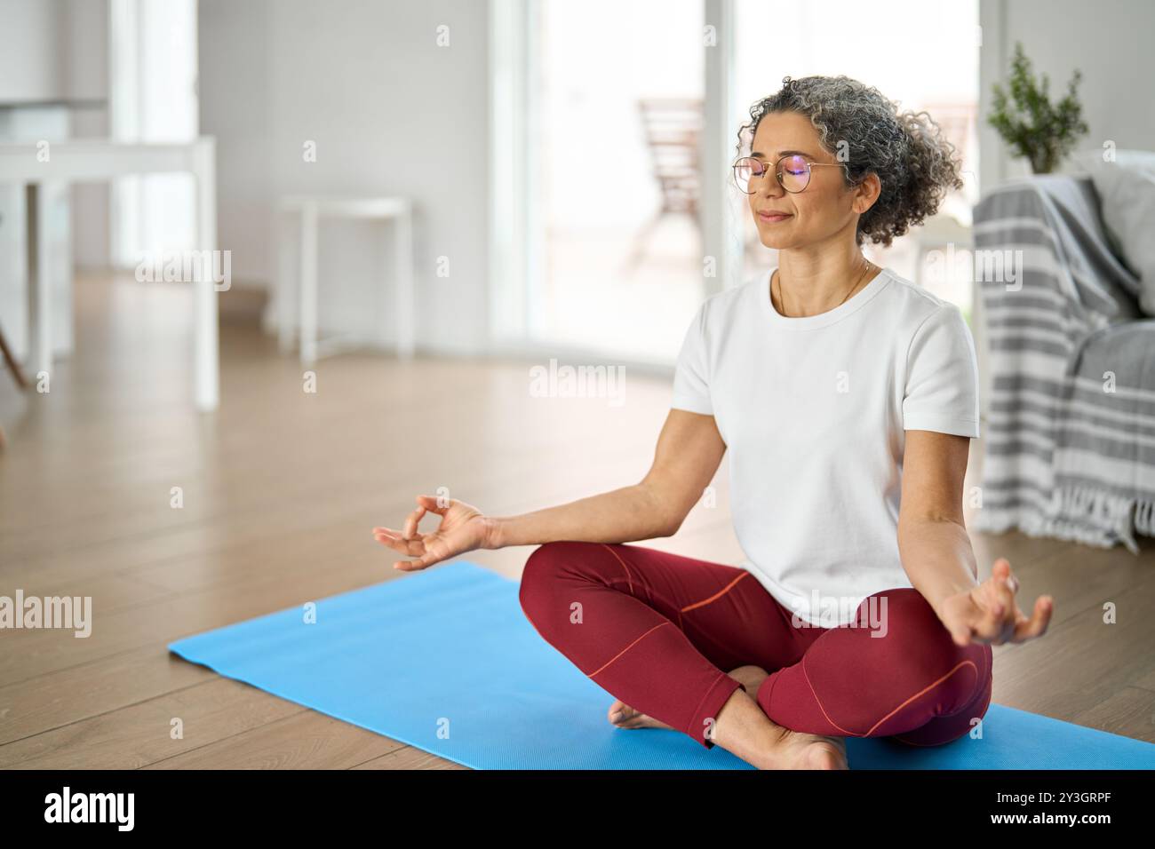 Happy healthy middle aged woman meditating at home doing breathing ...