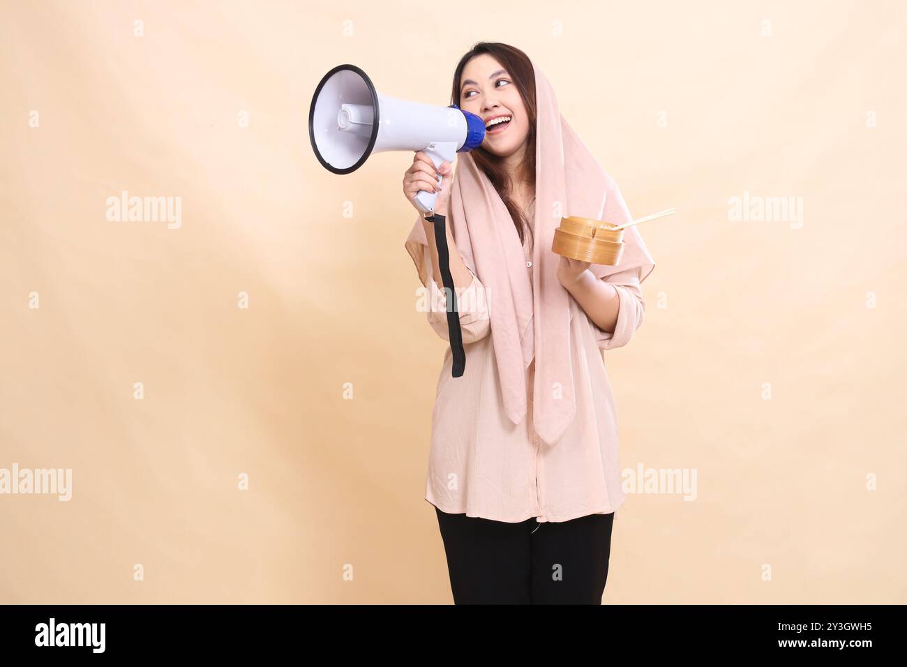 young Asian woman looks to the left screaming happily carrying a ...